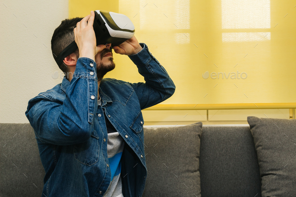Young man wearing virtual reality goggles inside his modern house ...