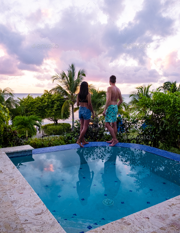 Young men and women watching sunset at the infinity pool at Saint Lucia ...