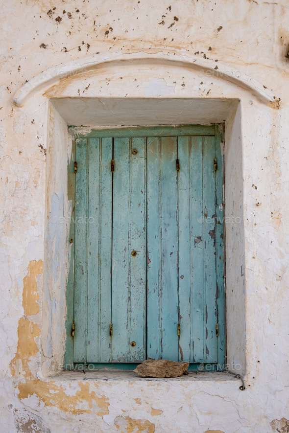 Aged wooden closed shutters, peeled building wall facade, stone keep ...