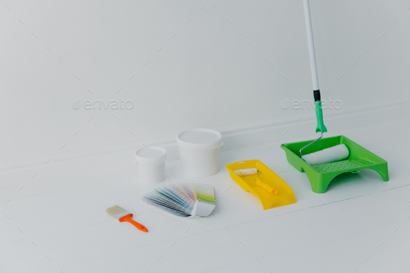 Paint roller in tray, paintbrush and color sample isolated over white ...