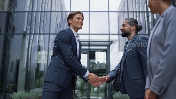 Thankful leader shaking hands greeting smiling team members at office ...