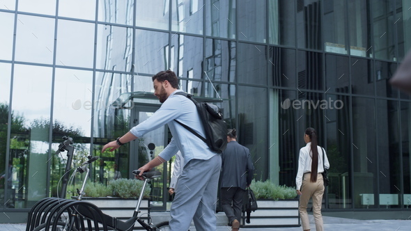 Manager riding bicycle leaving office workplace. Modern city mobility ...