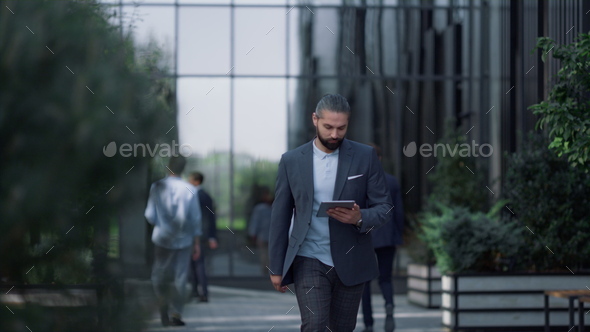Focused manager walking with tablet at modern office building. Career ...