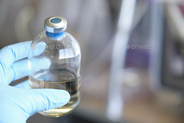 Researcher hand wearing gloves holding a bottle for anaerobic cultures ...