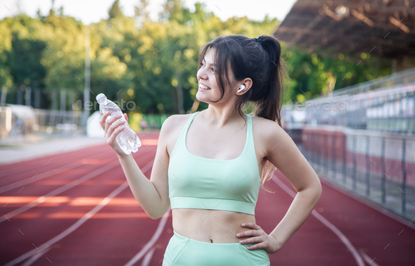 A young woman with a bottle of water in training at the stadium. Stock ...