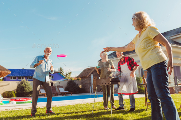 Senior people having fun playing outdoor games and making barbecue in ...