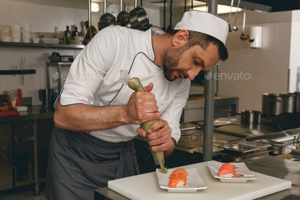 Handsome Male Chef in uniforms preparing sushi in a kitchen of asian ...