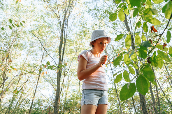 child naturalist botanist with a magnifying glass is surprised and ...
