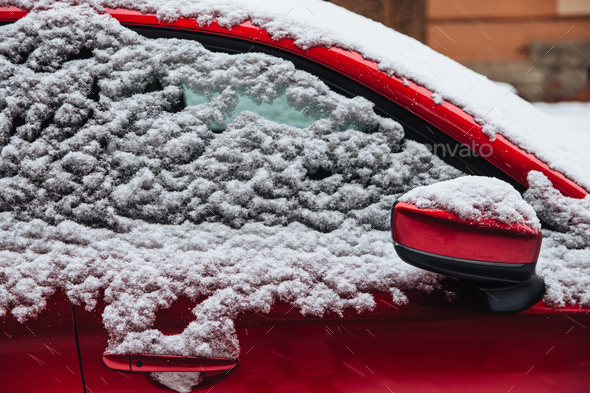 Red car covered with thick snow. Winter blizzard and bad weather ...