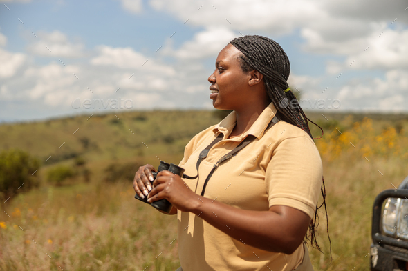 Female tour guide searching the landscape for wildlife in Africa Stock ...