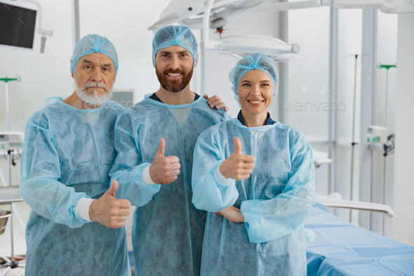 Team of professional surgeons shows thumbs up standing in operating ...