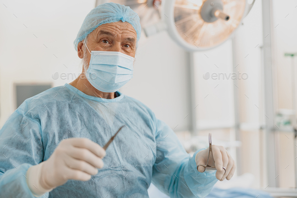 Professional doctor surgeon holding scalpel and forceps in operation ...
