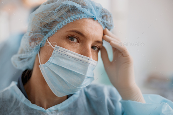 Close up of tired surgeon in mask standing in operating room after ...