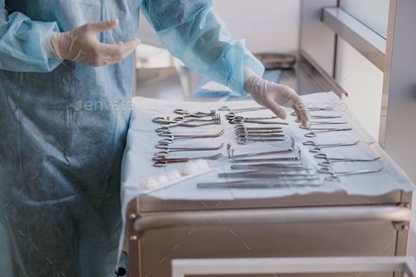 Nurse hand taking surgical instruments from table for a surgery during ...