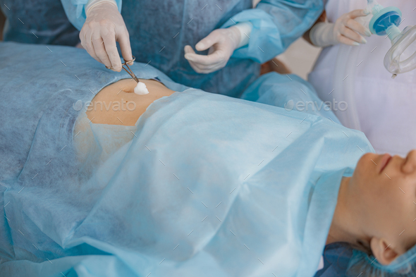 Nurse and doctor prepare patient skin for surgery using antiseptic ...