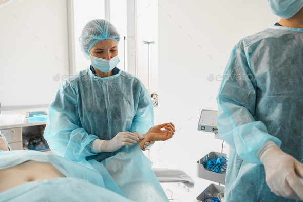 Doctor surgeon checking patient pulse during surgery in operation room ...