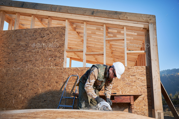 Carpenter using circular saw for cutting OSB board for building wooden ...