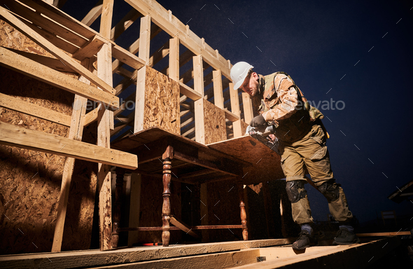 Carpenter using circular saw for cutting OSB board for building wooden ...