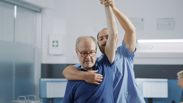 Medical assistant raising arms of elder person to stretch muscles Stock ...