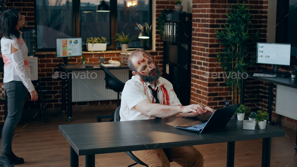 Scary zombie sitting in office while working on modern laptop. Stock ...