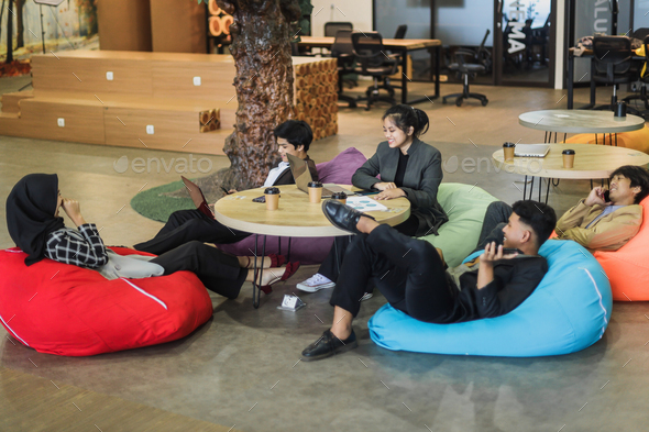 Business people sitting on bean bag chair during break time Stock Photo ...