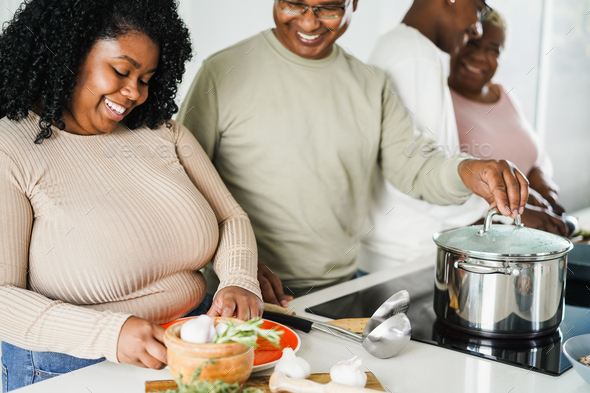 Happy black family cooking inside kitchen at home - Focus on girl face ...