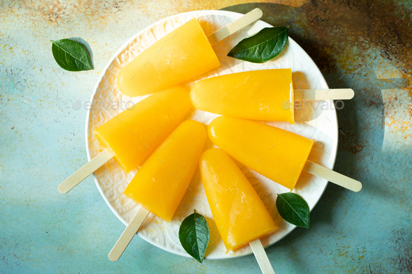 Orange popsicles with juice on a rusty blue bacground. Ice pops, flat ...
