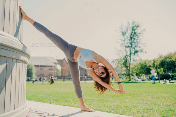 Flexible slim woman does stretching exercises outdoor stays in good ...