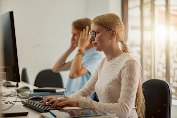 Focused university student using computer studying in computer room ...