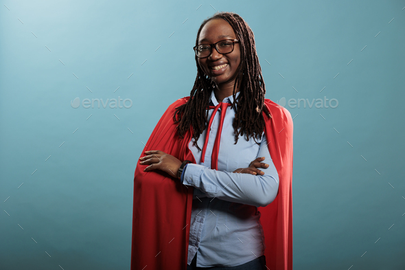 Portrait of happy brave woman with superpowers wearing red hero cape ...