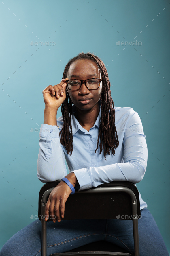 Portrait shot of young attractive woman casually sitting on chair with ...