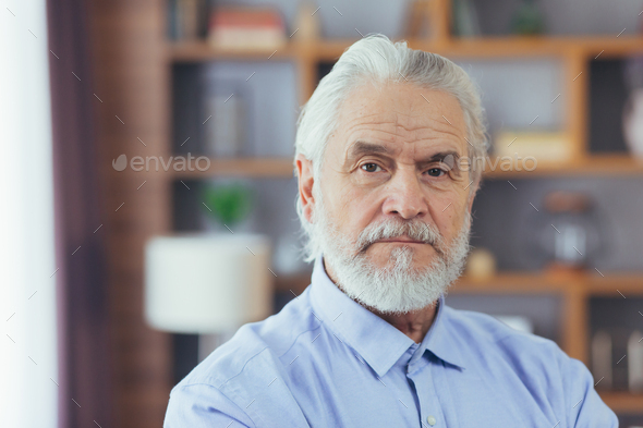 Close-up photo of portrait of old man at home, looking at camera and ...