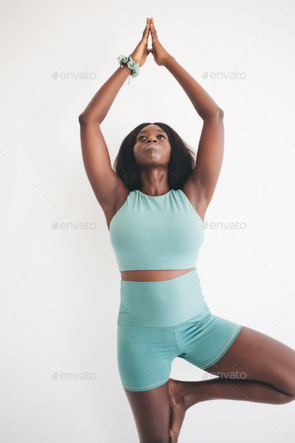 dark skinned female healing in tree and namaste pose during hatha yoga ...