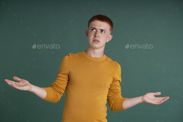 Frustrated caucasian teenage boy of ginger hair with arms outstretched ...