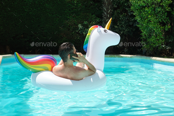 Business man talking on the phone backwards on a unicorn inflatable ...