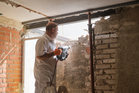 Builder with demolition hammer breaking a house wall. Stock Photo by ...