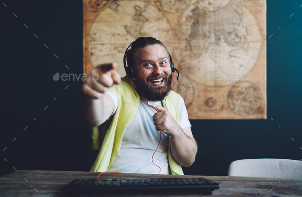 Excited guy smiling and pointing at screen while playing computer game ...