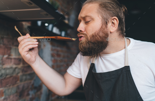 Male chef trying pasta during cooking in kitchen at home Stock Photo by ...
