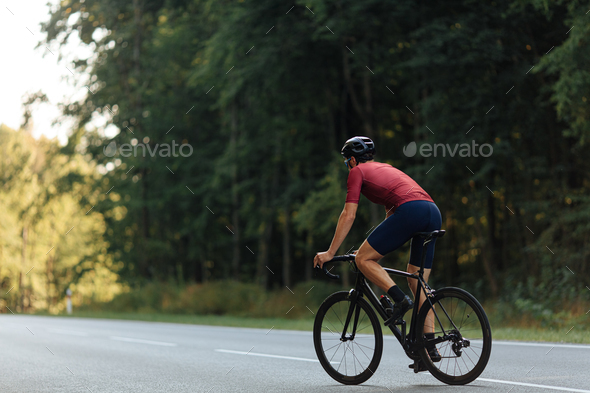 Back view of muscular guy in helmet riding bike on road Stock Photo by ...