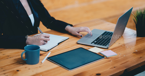 Close-up of a woman hand taking notes with various items placed on the ...