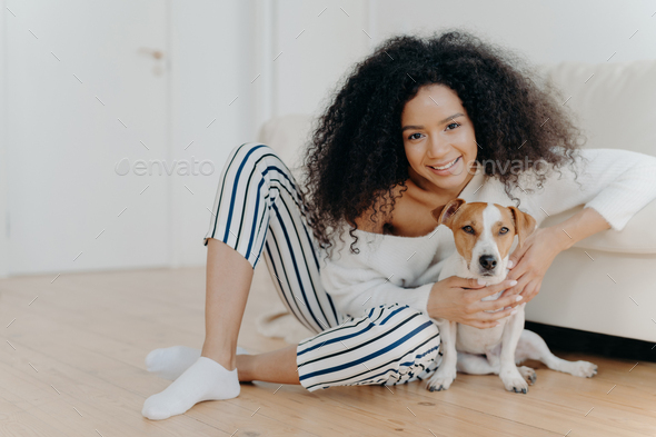 pleased curly haired female model poses for photo with jack russell ...