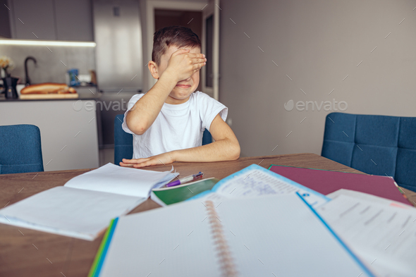 Funny sad little Caucasian schoolboy crying and closing eyes with hands ...