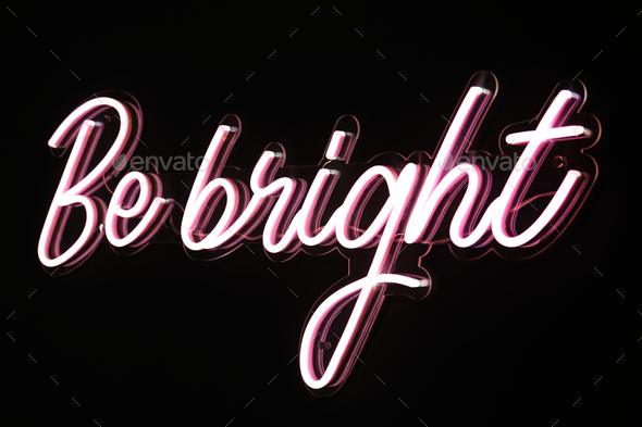 Be bright phrase in pink flashing neon letters over black background ...