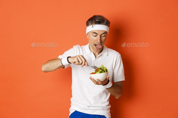 Portrait of funny middle-aged sportsman in workout uniform, licking ...