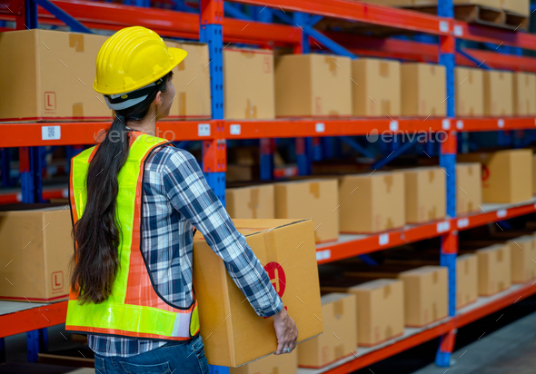 Back of warehouse worker woman hold the box and bring to shelves in ...