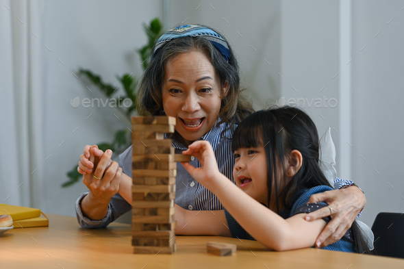 Little asian child and grandmother having fun playing wood block ...