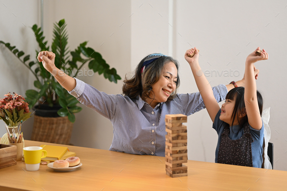 Overjoyed little asian girl and grandmother playing wood block stacking ...