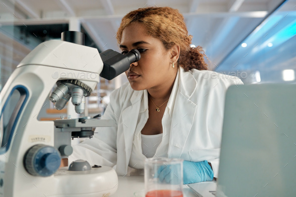 Shot of a young female lab worker analysing samples through a ...