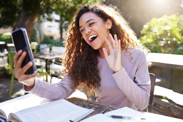 Shot of a young female student using a phone while studying at a cafe ...