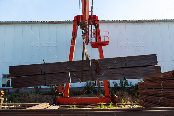 Gantry crane transporting stack of metal pipes Stock Photo by collab_media